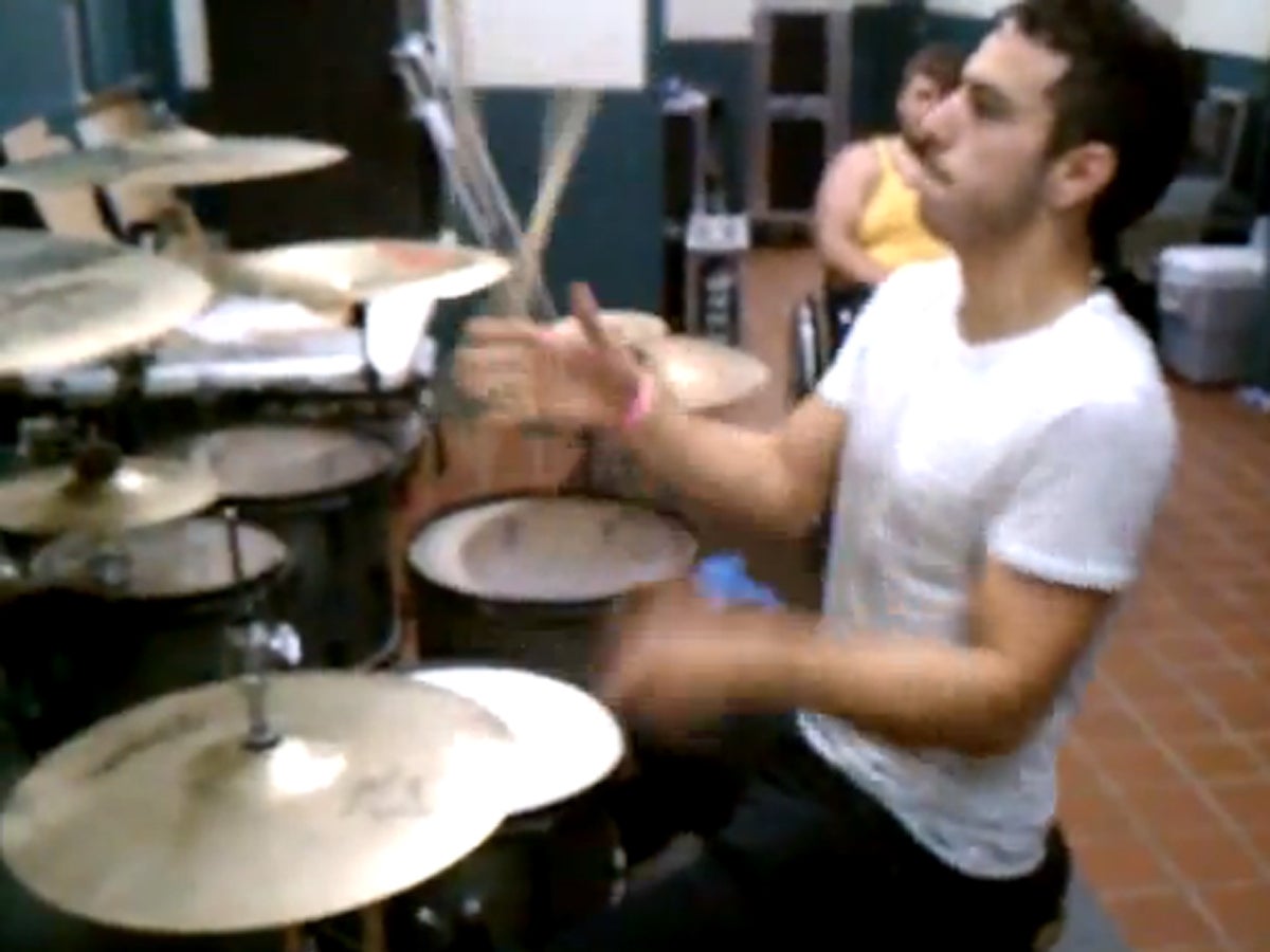 Musician Adam Gray juggling three sticks while drumming - CBS News