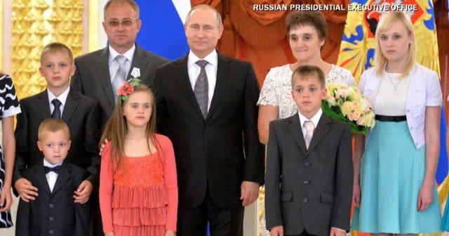 Vladimir Putin poses with "happy" families in awkward photos - CBS News